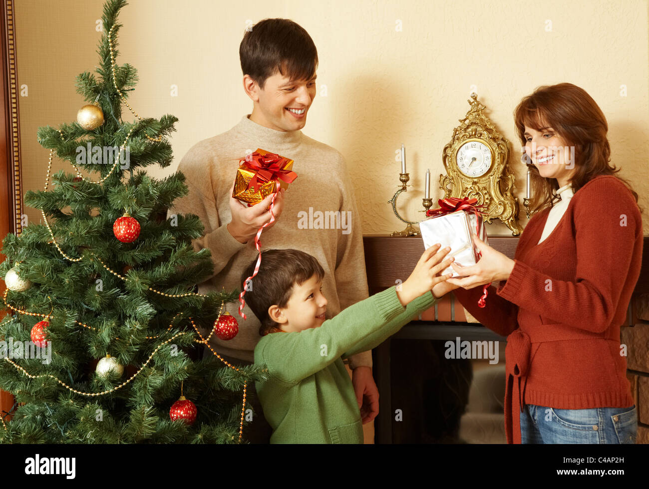 Portrait of happy boy giving present to mother with his father near by ...