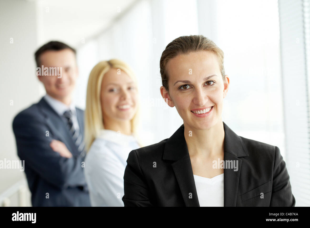 Portrait of pretty leader looking at camera with two partners behind ...