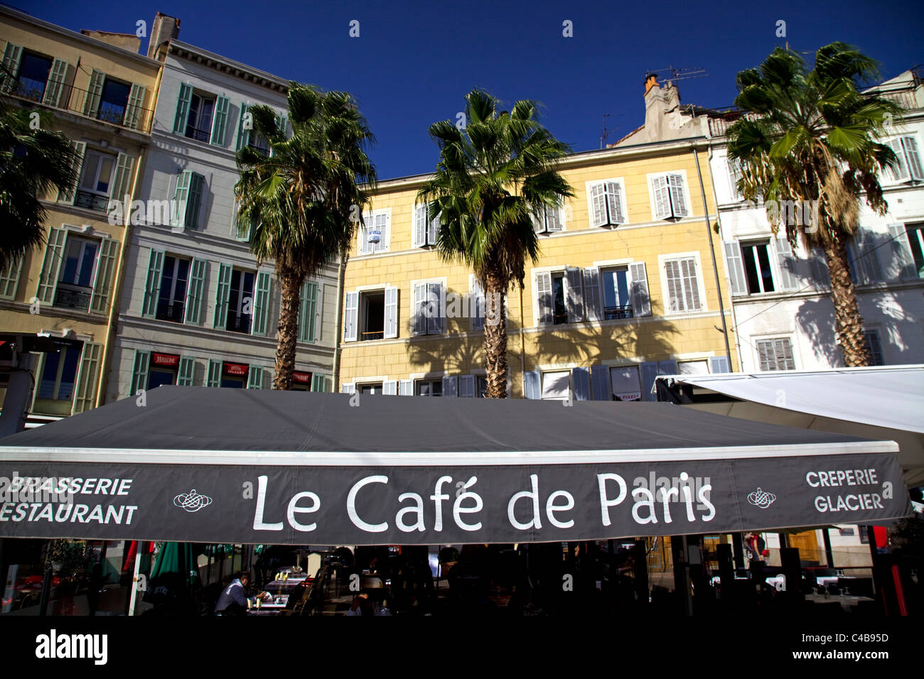 Marseille, Provence, France; A cafe amidst building and palm trees ...