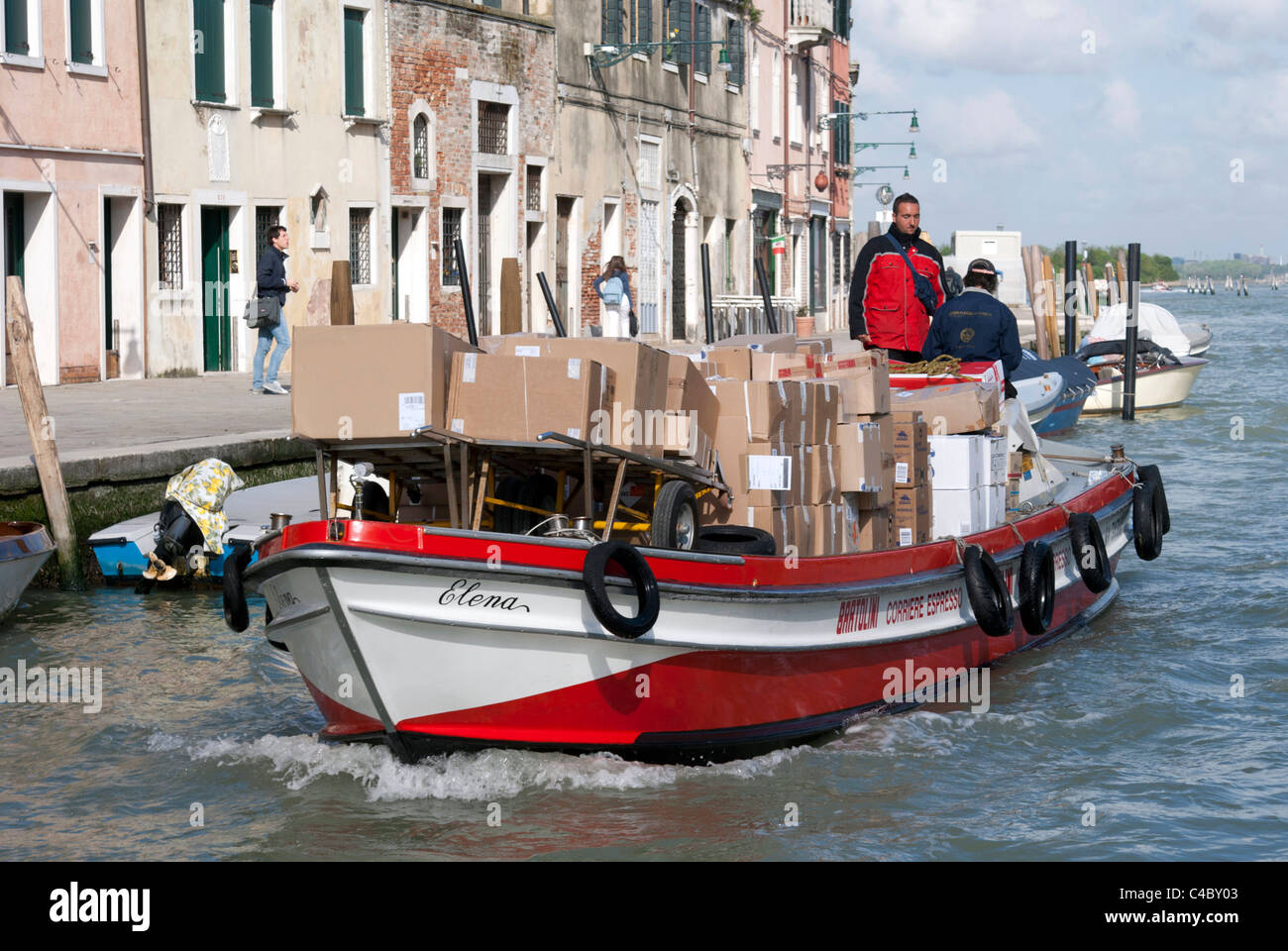 A heavily loaded delivery boat entering the Grand Canal in Venice ...