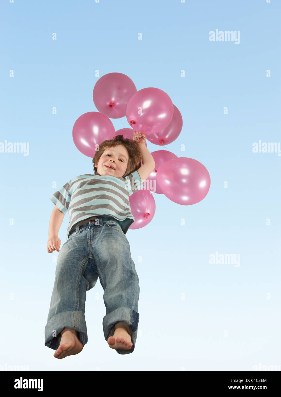 Boy jumping with bunch of balloons Stock Photo - Alamy