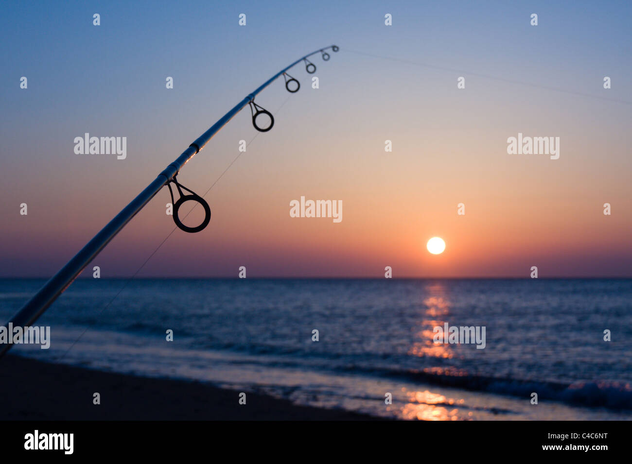 A fisherman sea angling as the sun sets on the coast at Marget, Kent ...