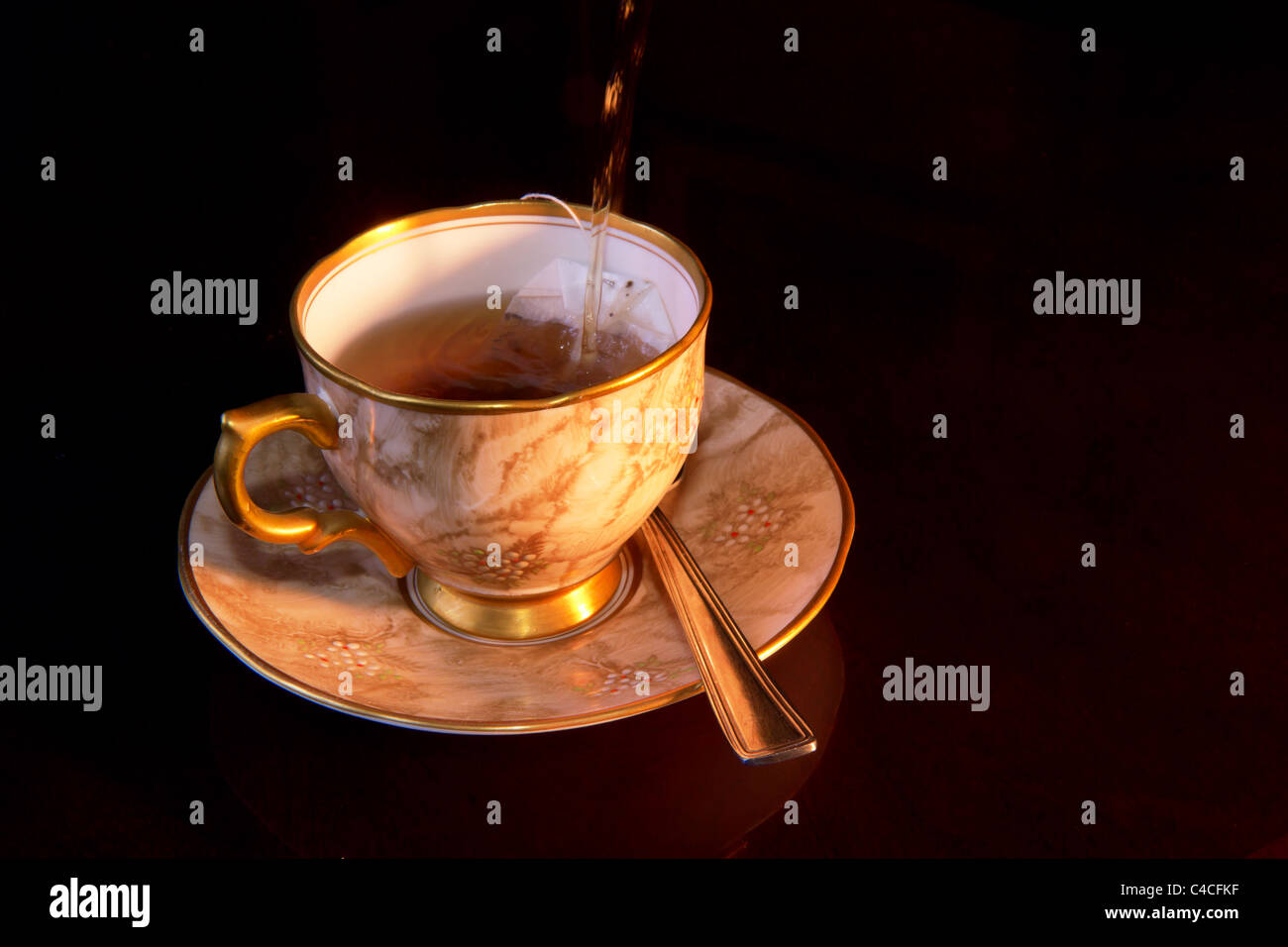 Boiling hot water being poured into a cup on a saucer with a tea bag ...