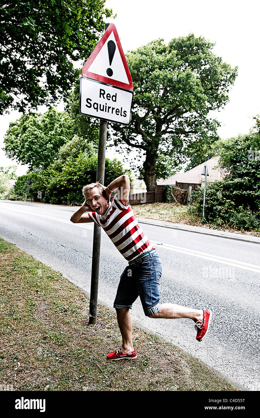 Frightened man screaming and holding his head in front of a red ...