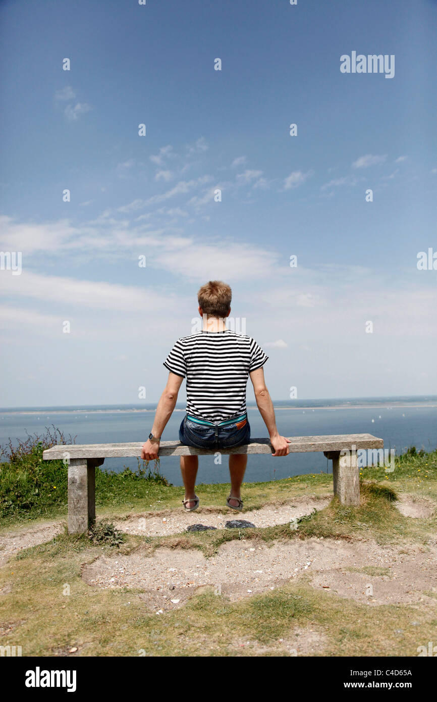 Rear view of a man wearing striped T shirt on holiday sitting on a ...
