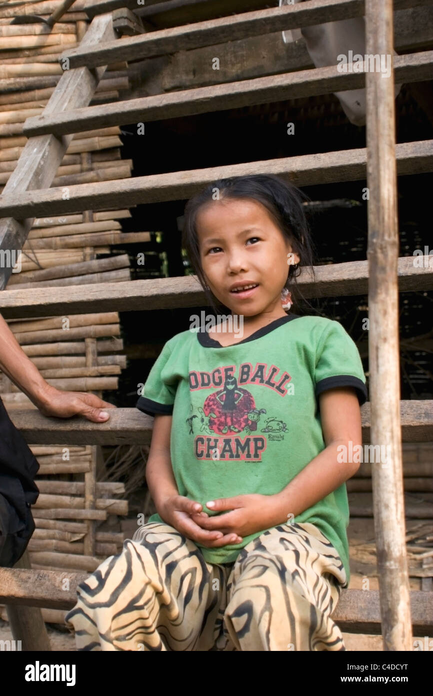 A young Asian girl living in poverty is sitting on the steps of her ...