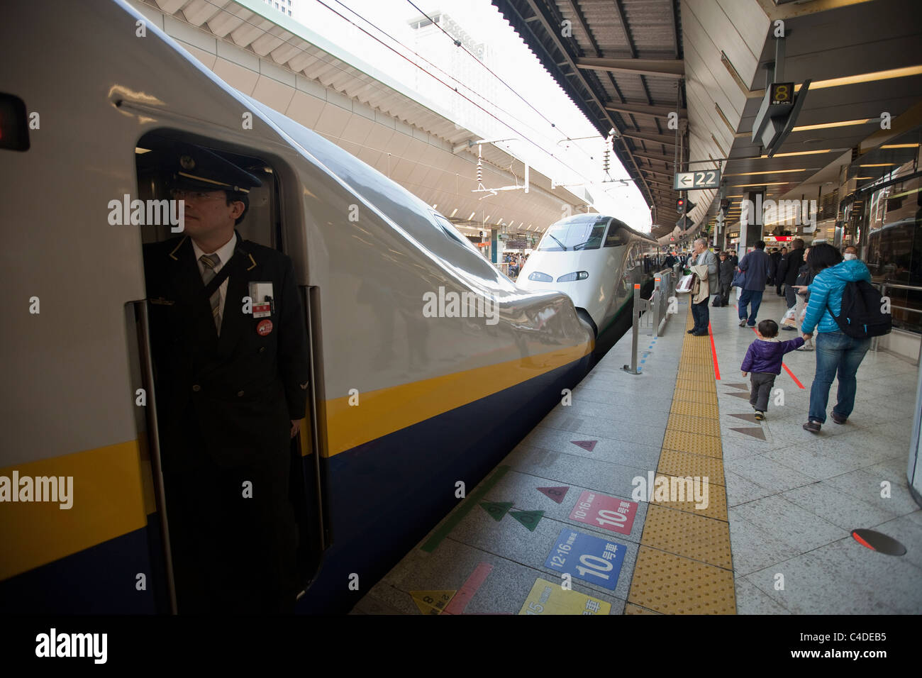 Bullet train, conductor, and passengers on platform at Tokyo station ...