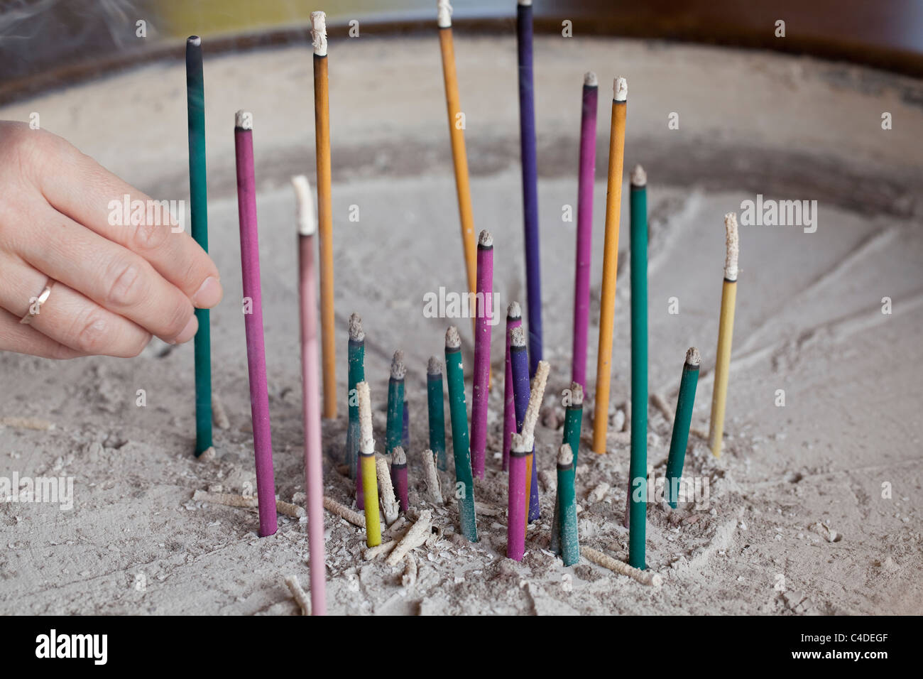Worshipper placing lighted stick of purifying incense in cauldron at ...