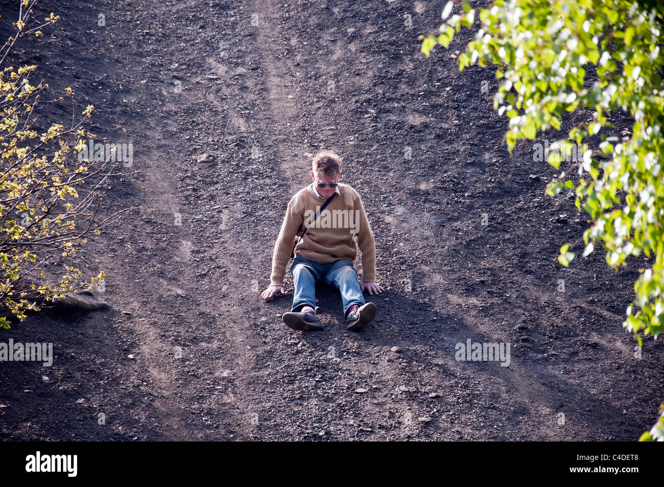 man sliding down slag heap in paulton somerset Stock Photo - Alamy