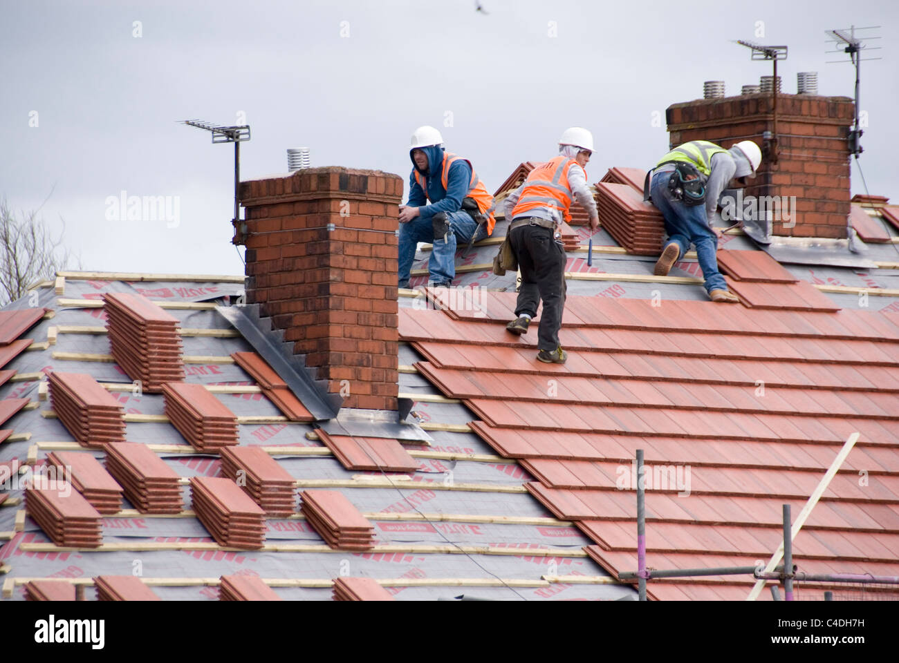 Three Men on Roof of House Laying New Roof Tiles, Re Roofing ACIS ...