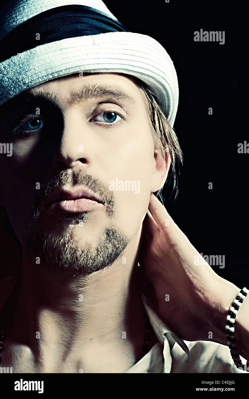 studio portrait of handsome young man in white hat on black background ...