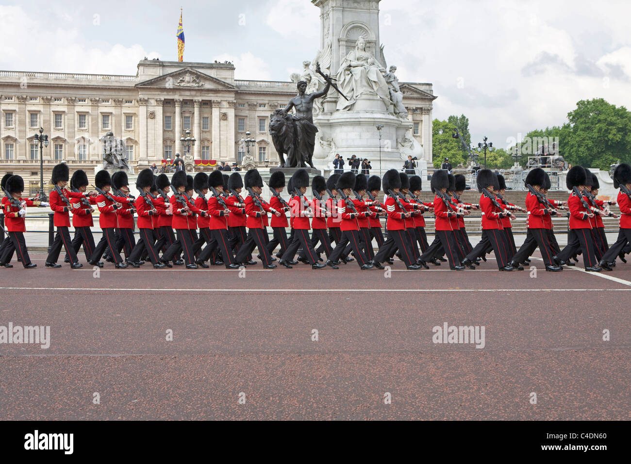 Soldiers marching past Queen Victorias statue outside Buckingham Palace ...
