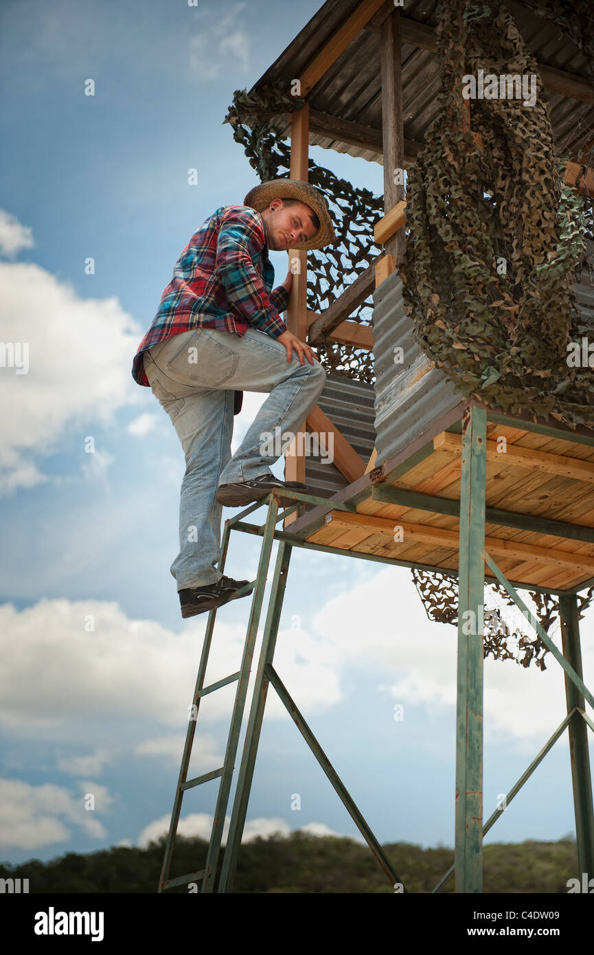 Young man climbing deer blind Stock Photo - Alamy