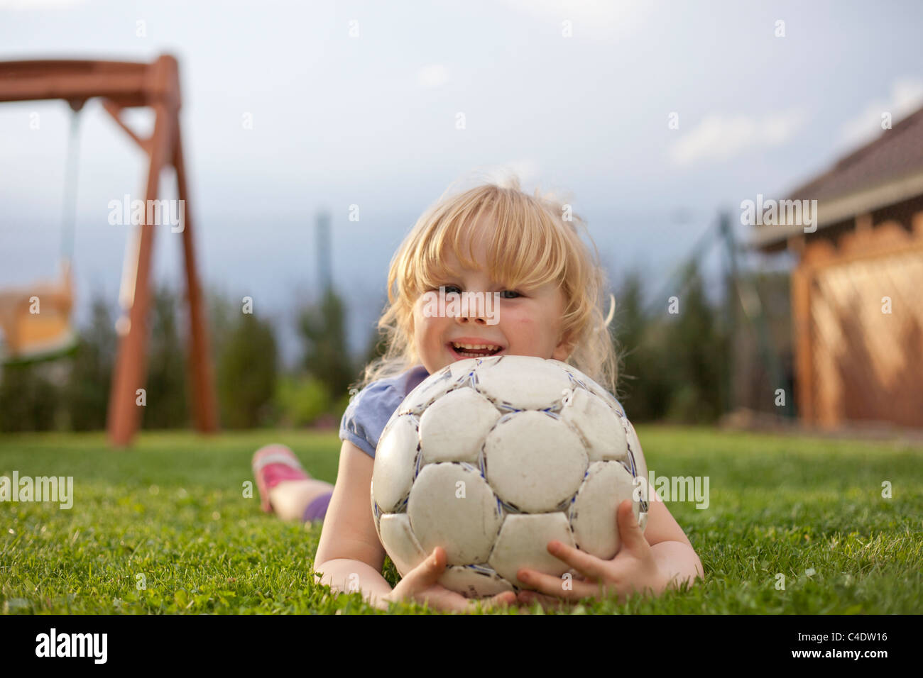 Young child lying on grass with a soccer ball, playful moment Stock ...
