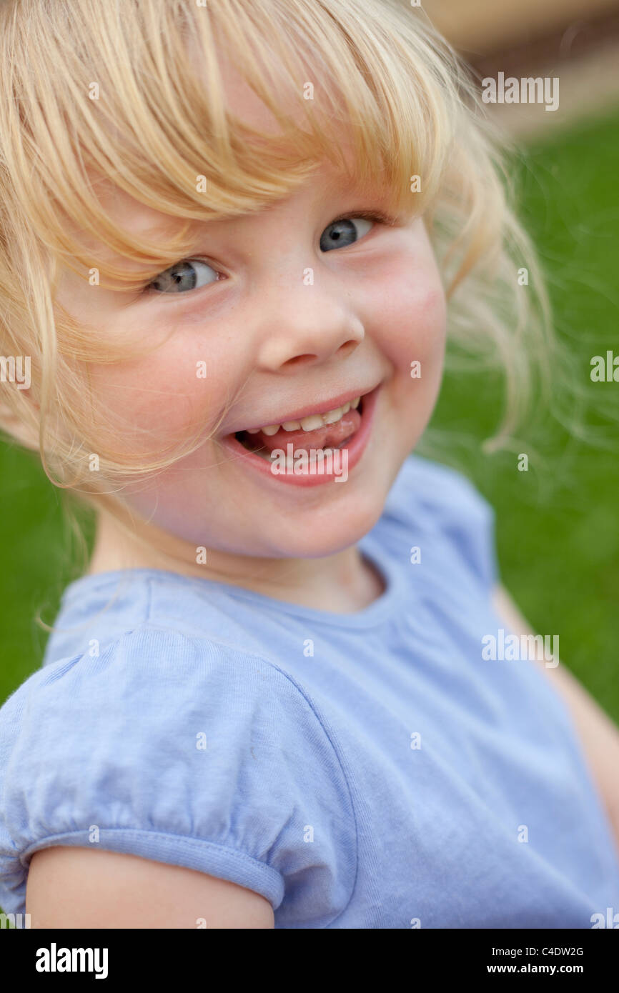 Playful toddler with a mischievous smile sitting in the garden Stock ...