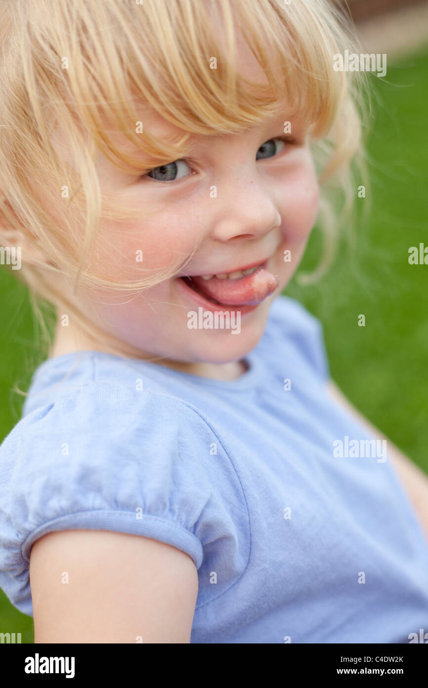 Playful toddler with a mischievous smile sitting in the garden Stock ...