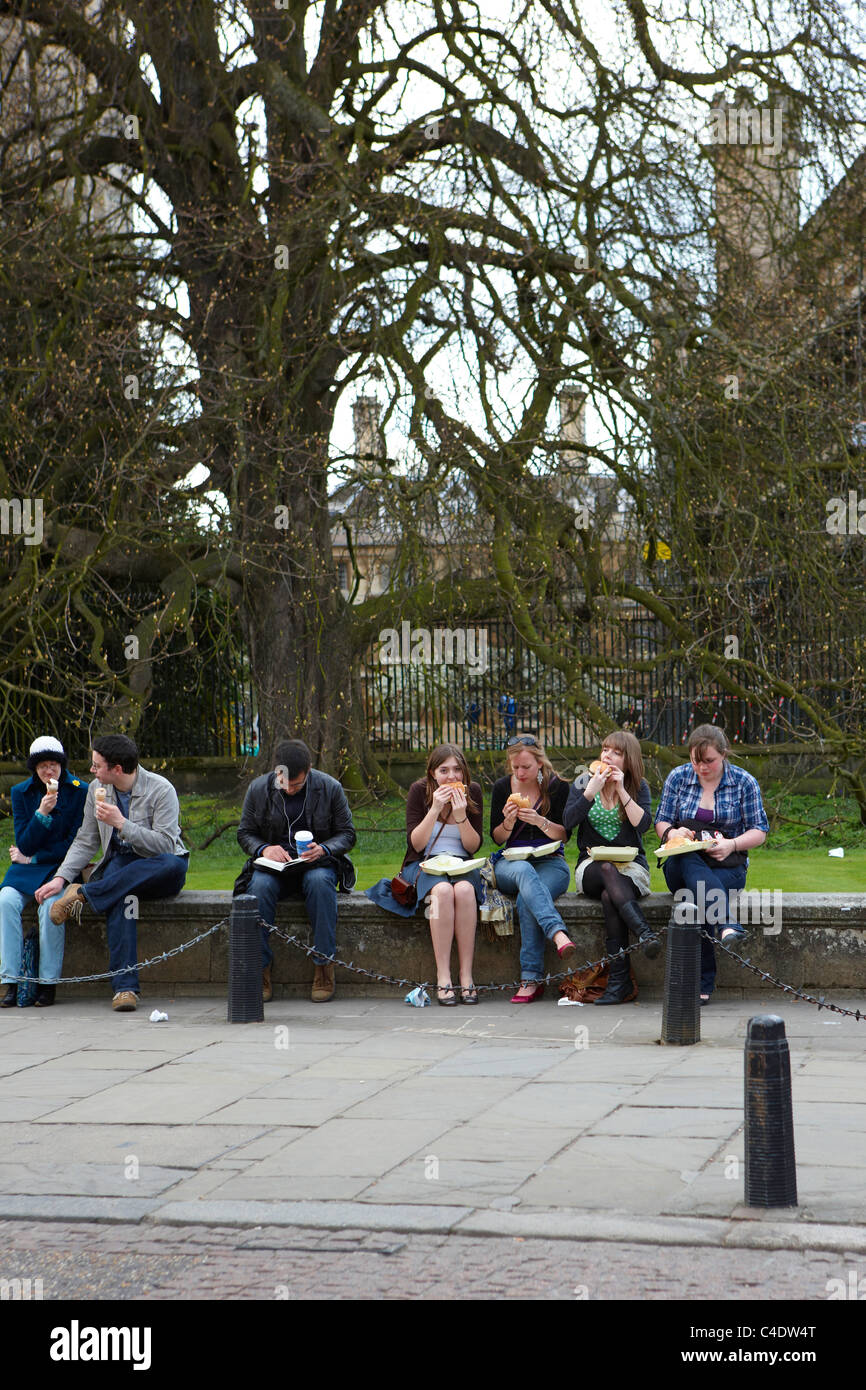 Group of people sat on a wall eating food Stock Photo - Alamy