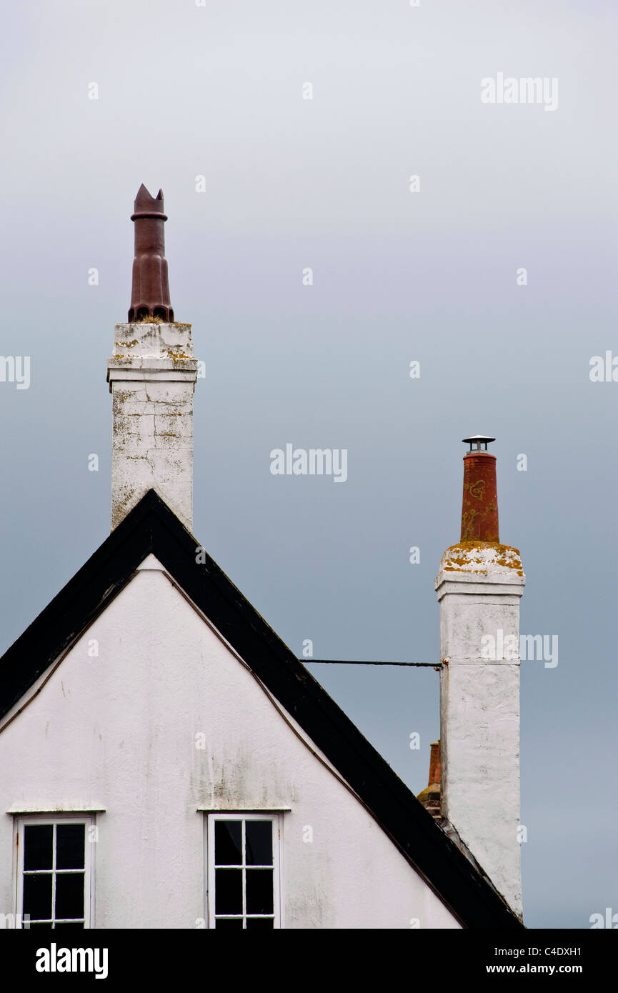 A white house with two tall chimney stacks and chimney pots. One ...