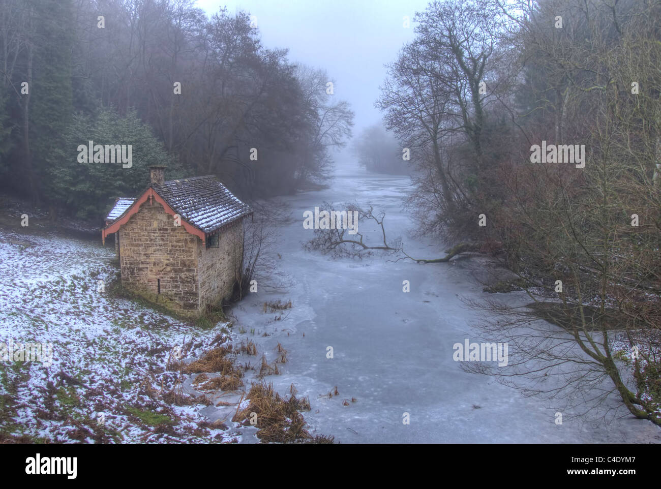 Winter scene frozen lake in a wood with picturesque period boathouse ...