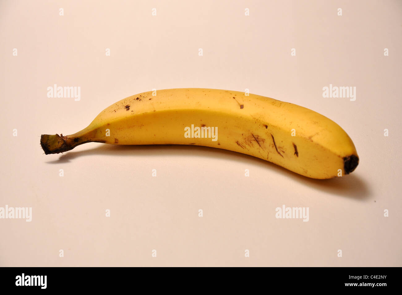 A lone banana lays on top of a white back ground Stock Photo - Alamy