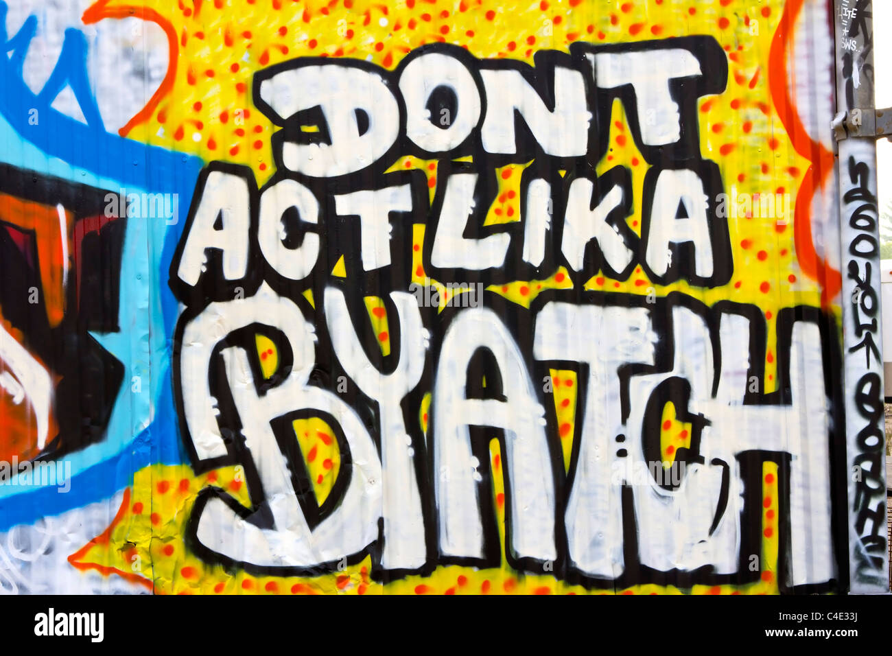 A White graffiti statement over a yellow and red polka dot background ...