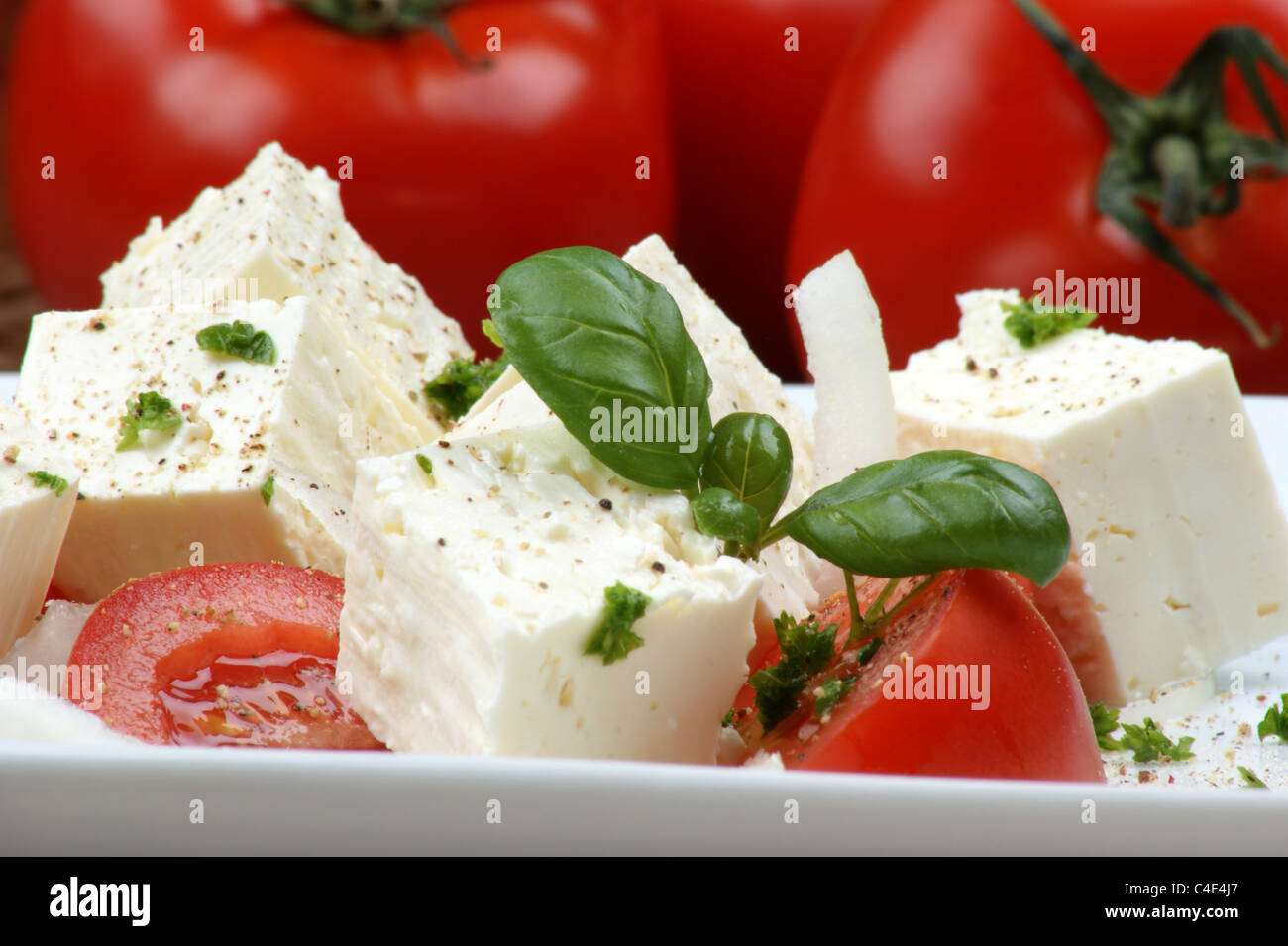 Greek goat cheese with tomato and basil Stock Photo - Alamy