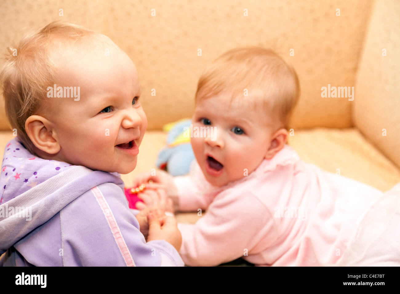 Two babies playing on sofa Stock Photo - Alamy