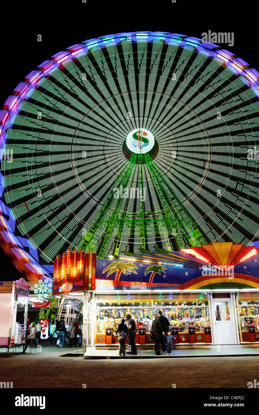 Family playing on crane grab stall at funfair in Spain with big wheel ...