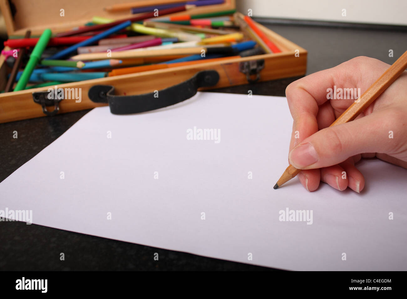 A hand holding a pencil poised ready to draw, sketch and colour on a ...