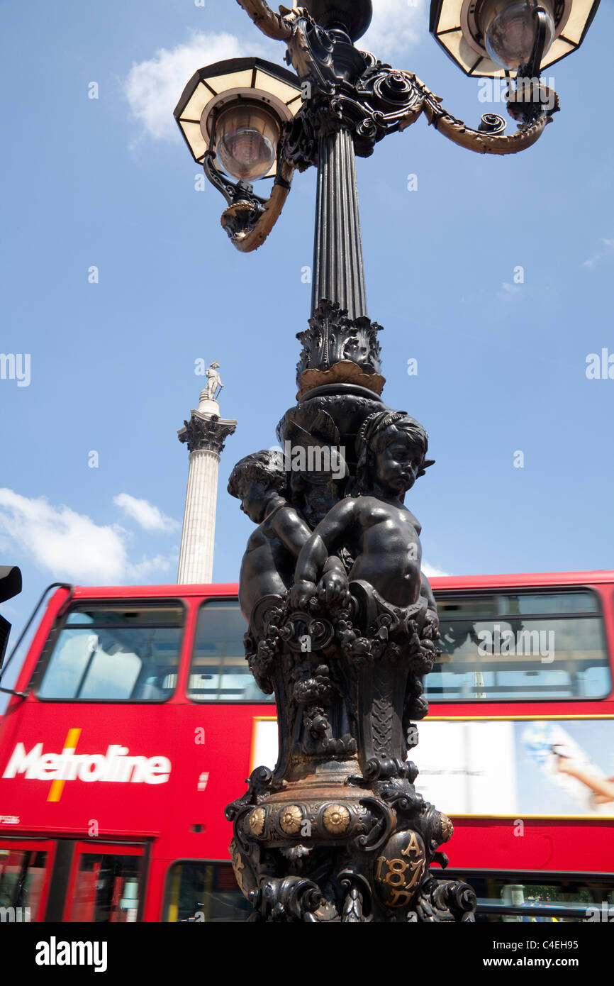 Bus passing ornate lamppost and Nelson's Column in London England Stock ...