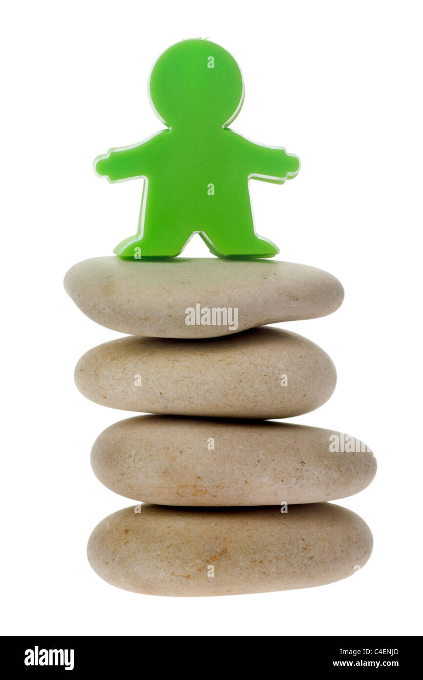 Green figurine on a stack of pebbles isolated on white background Stock ...