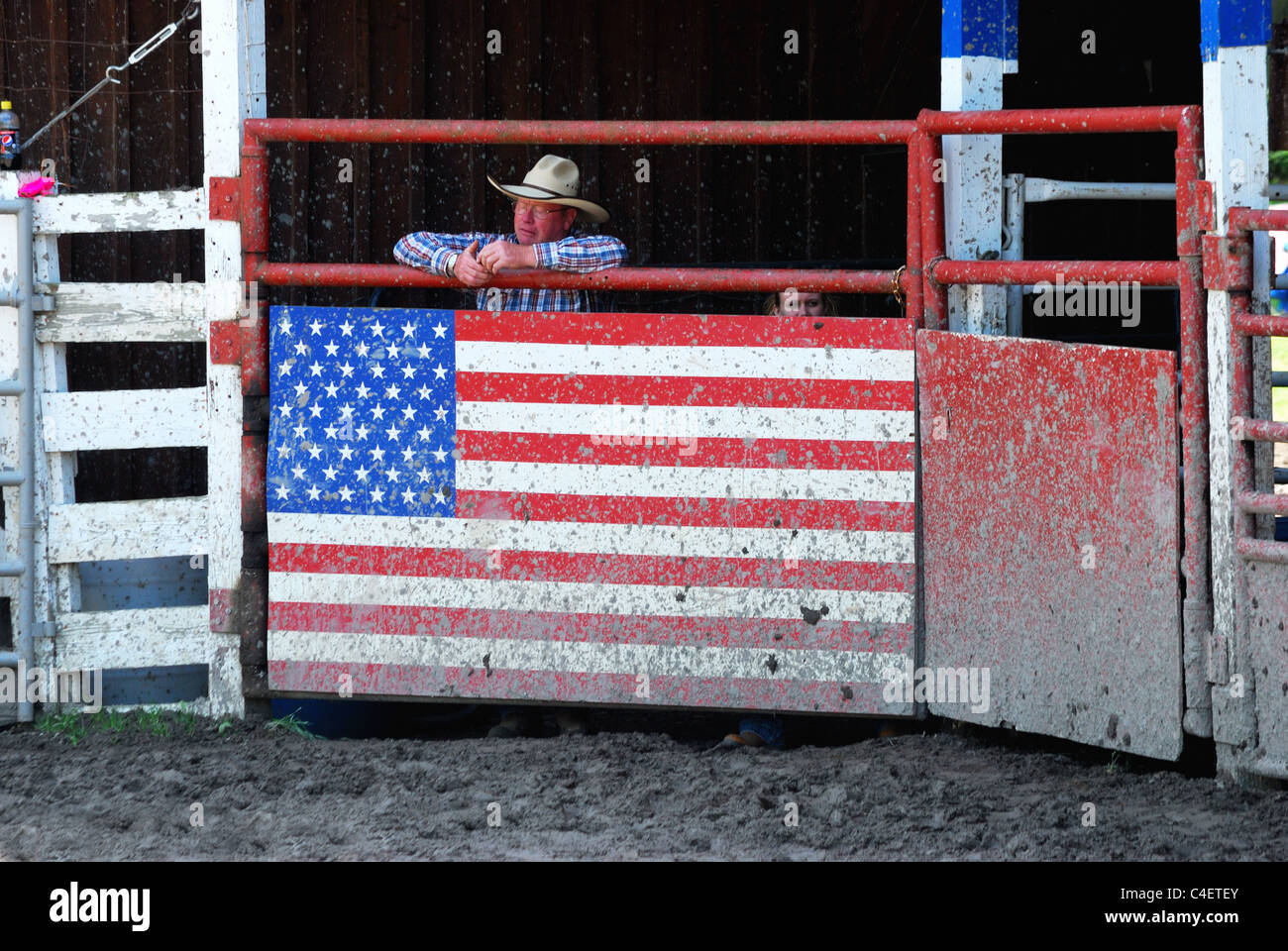 Rodeo official stands behind mud spattered gate Stock Photo - Alamy