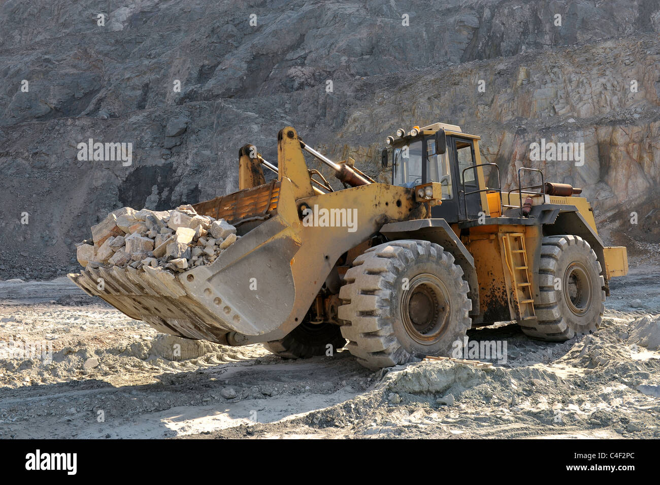 Wheel loader machine unloading rocks in the open-mine of iron ore Stock ...