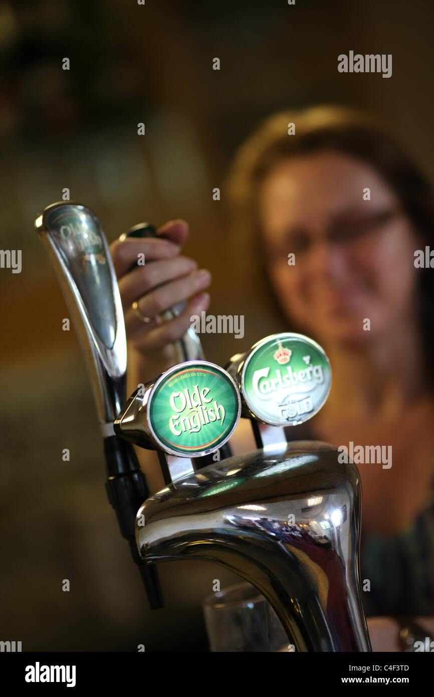 A woman pours Draft beer from a pump. Picture by James Boardman Stock ...