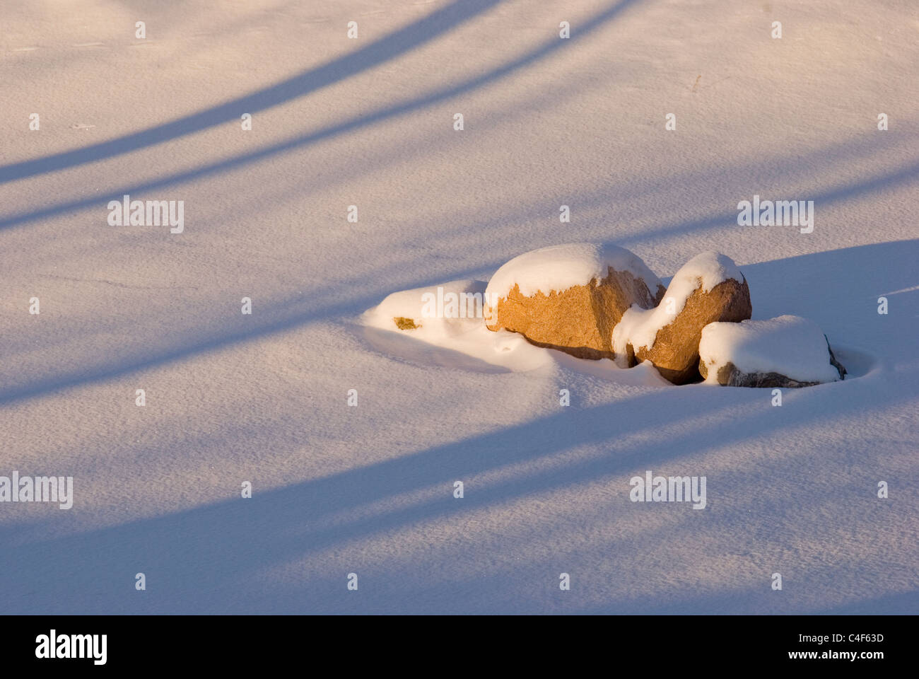Few huge stones covered with snow in white fields. Spring shadows on ...