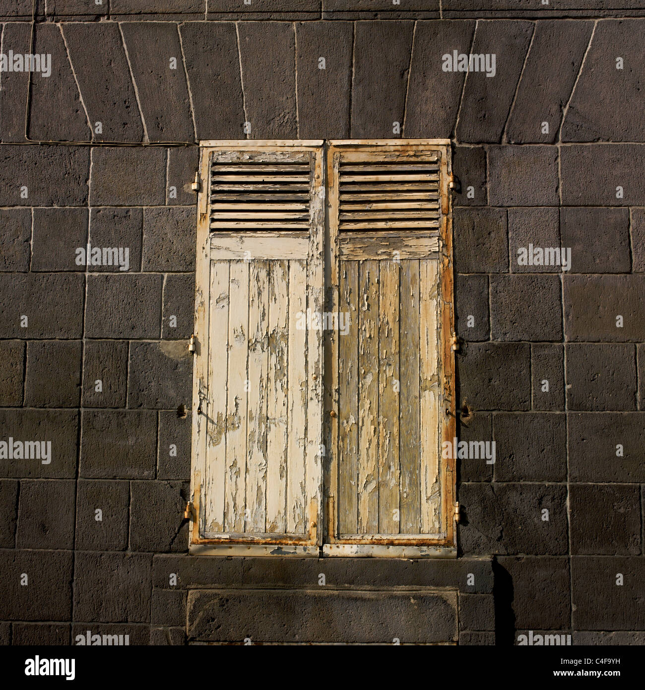 Weathered wooden shutters on a stone wall in an urban setting at night ...
