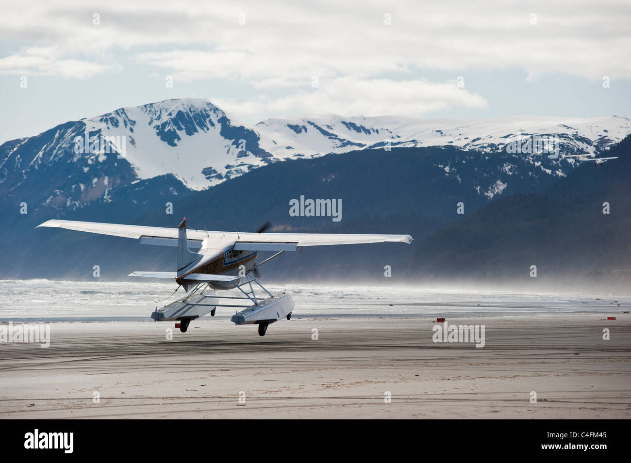 Cessna 185 on amphibious floats taking off from the beach on ...