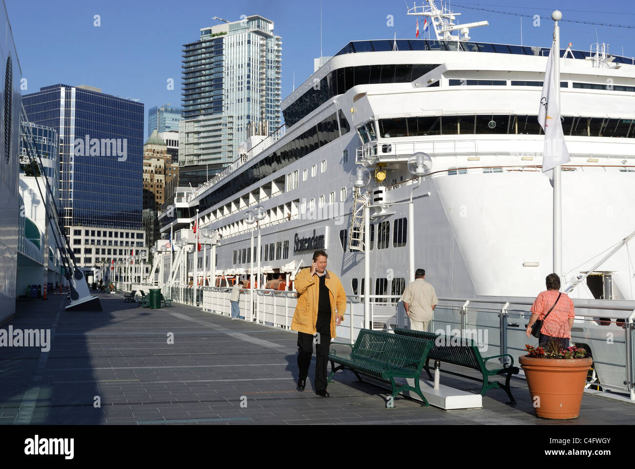People strolling along the walkway of Canada Place alongside the docked ...