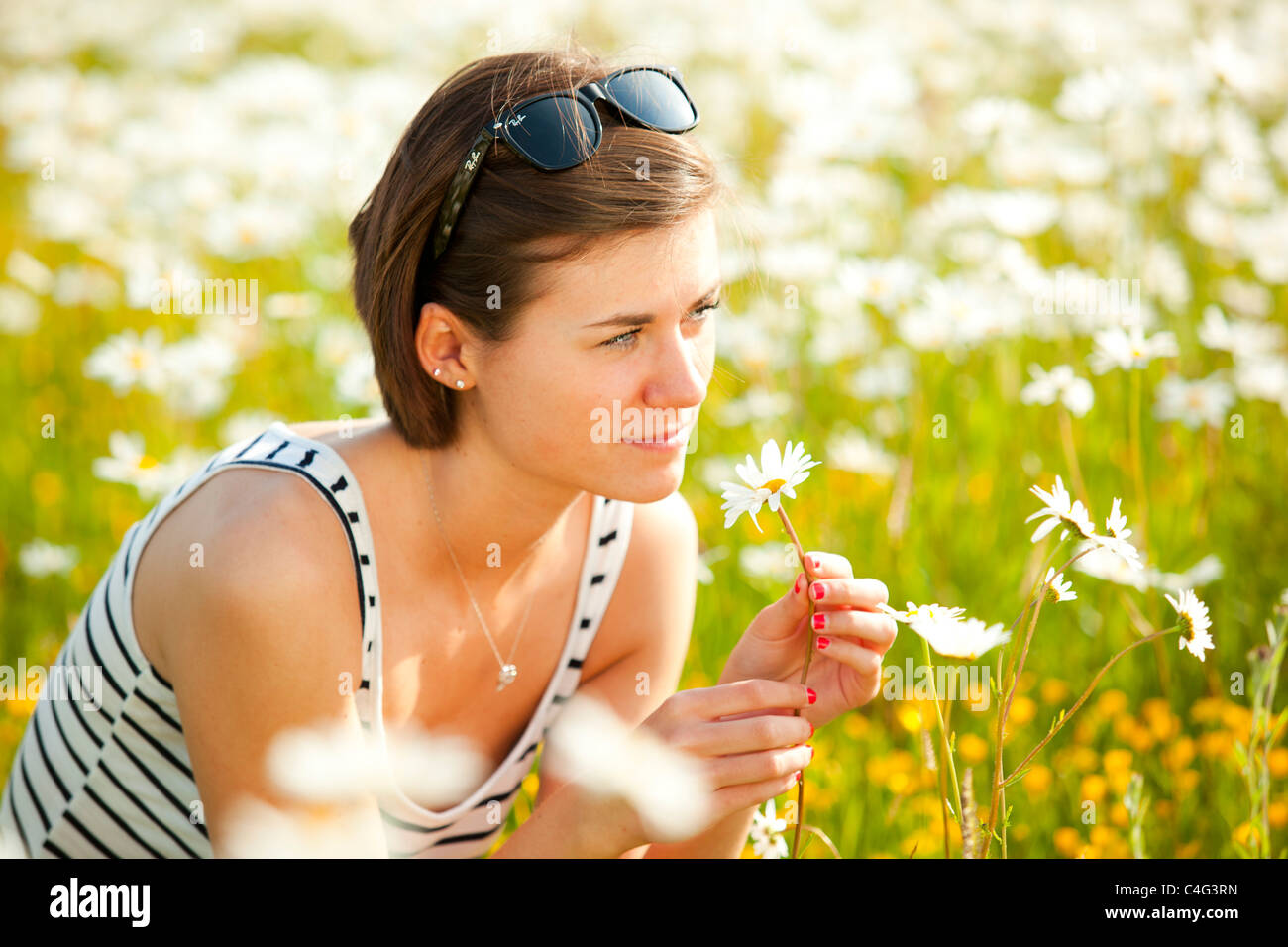 Girl smelling flower in field Stock Photo - Alamy