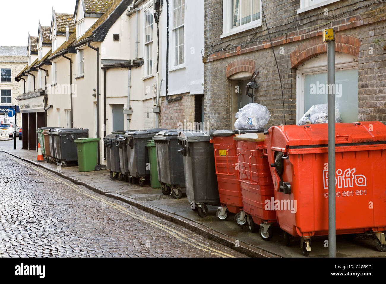 Cobbled side street rubbish bins awaiting collection Stock Photo - Alamy