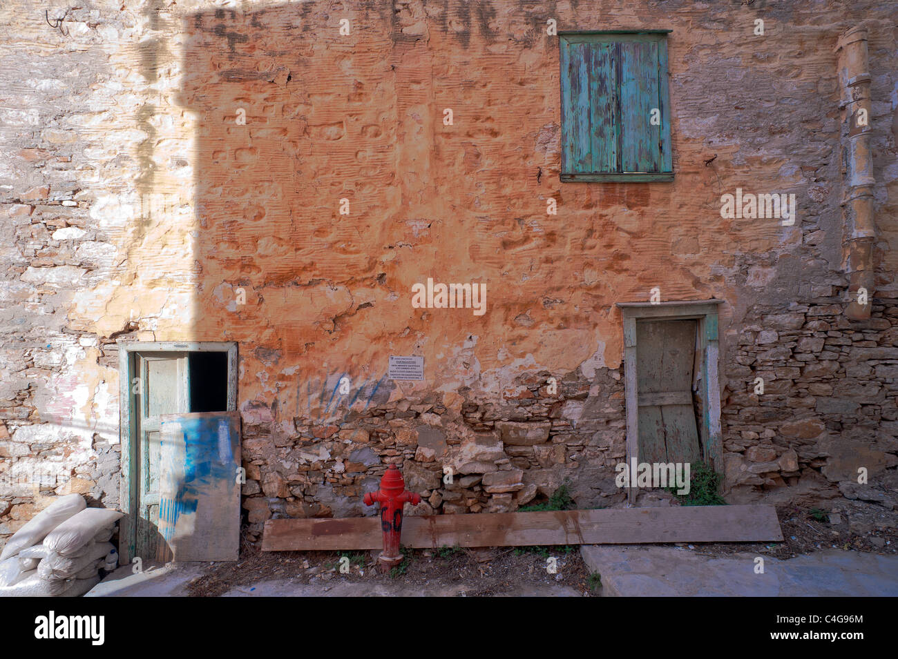 Fire hydrant against an old, decrepit stone wall in Ermoupolis, on the ...
