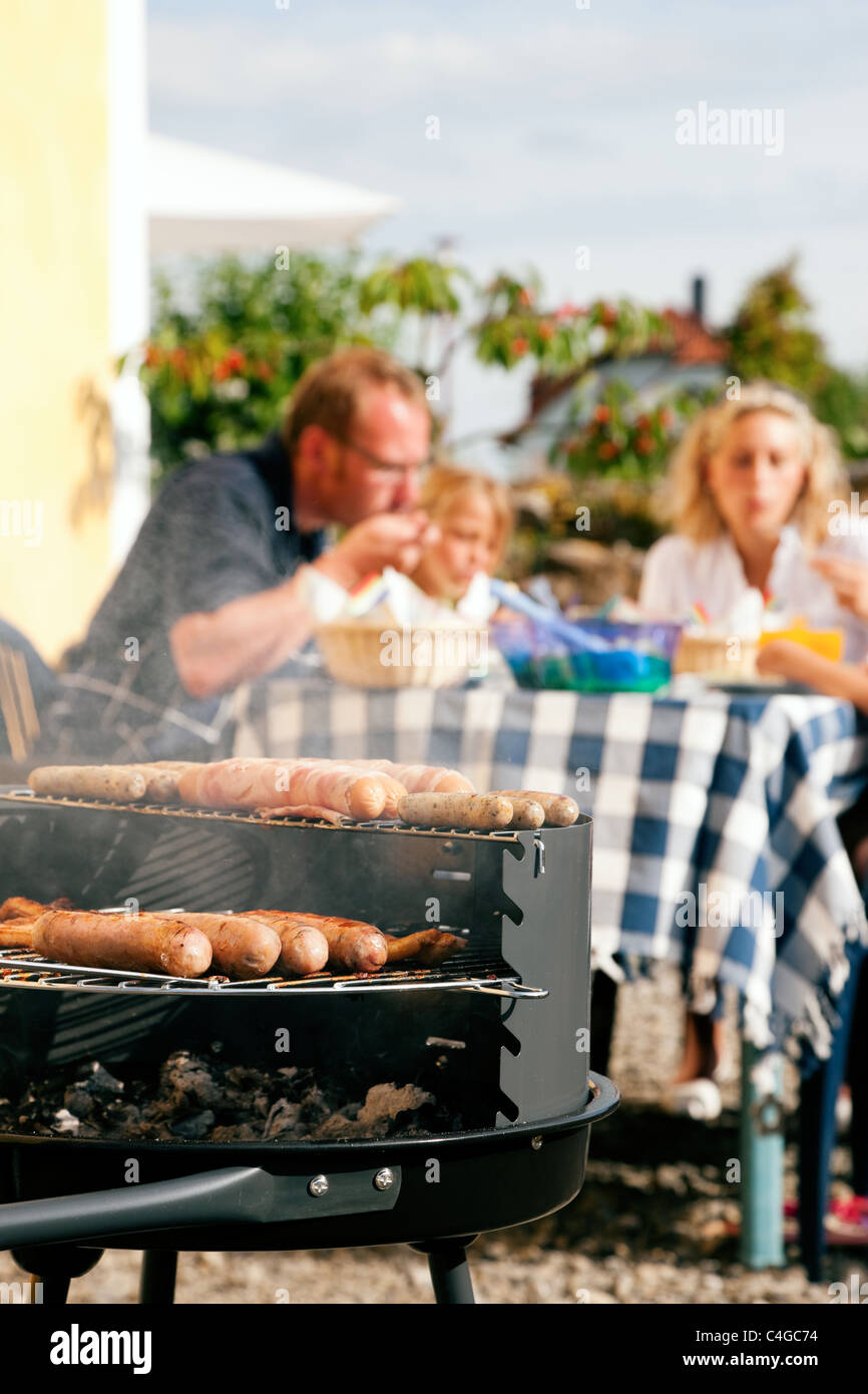 Family having a barbecue in the garden - focus on cooking in the ...