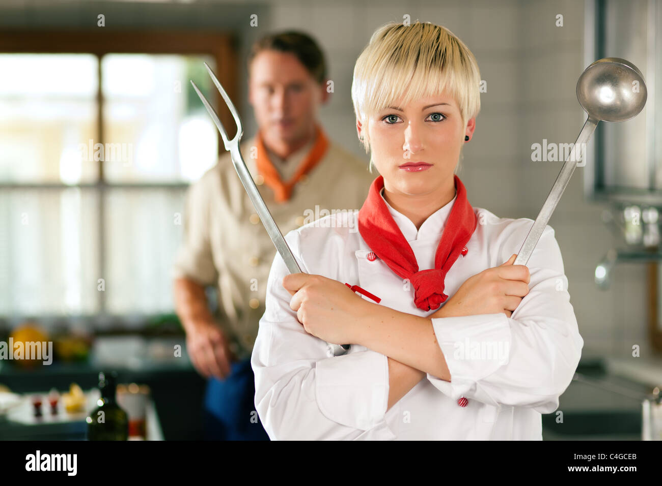 Female Chef in a restaurant or hotel kitchen posing with kitchen gear ...
