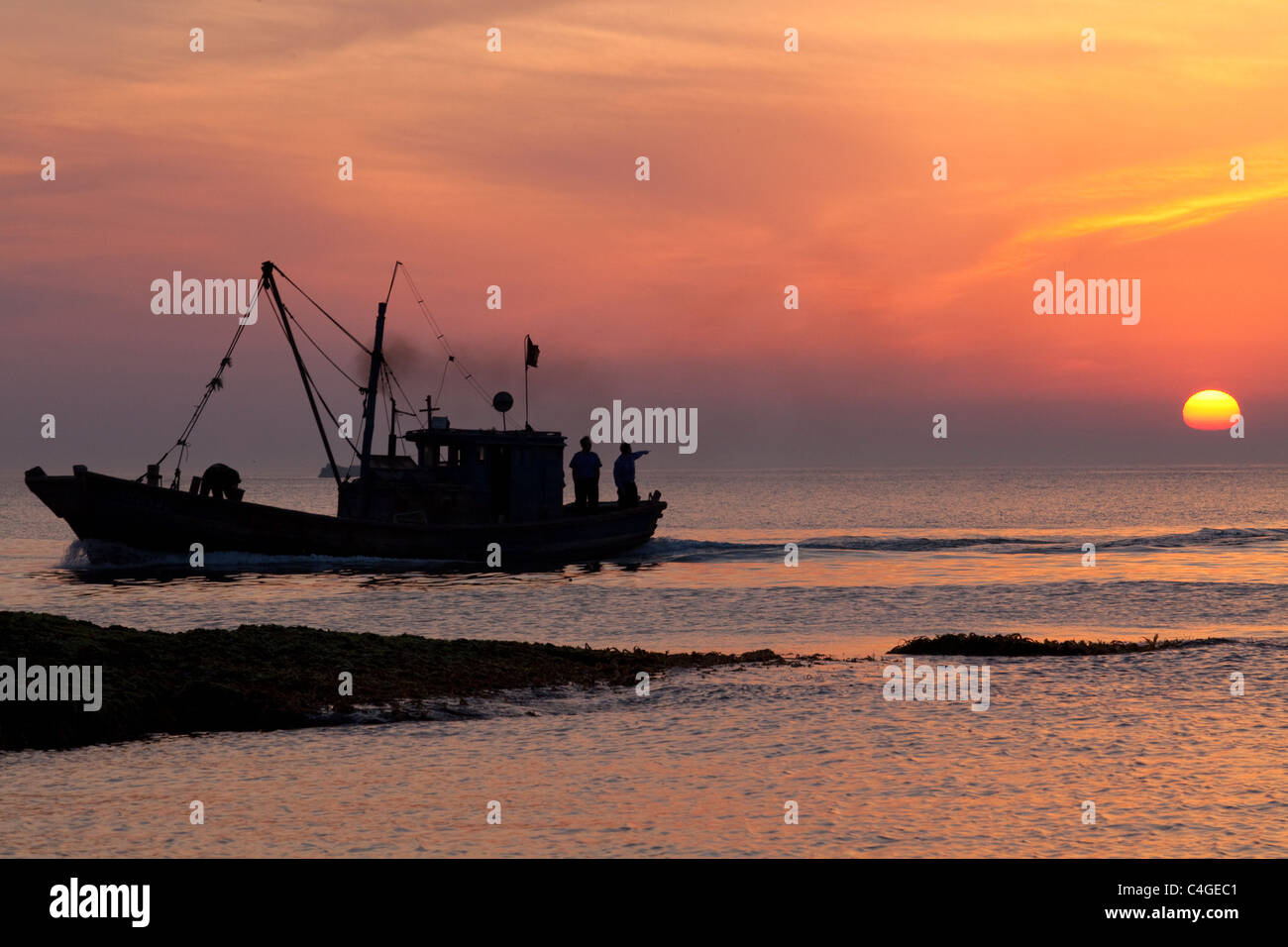 Fishing boat during sunset Stock Photo - Alamy