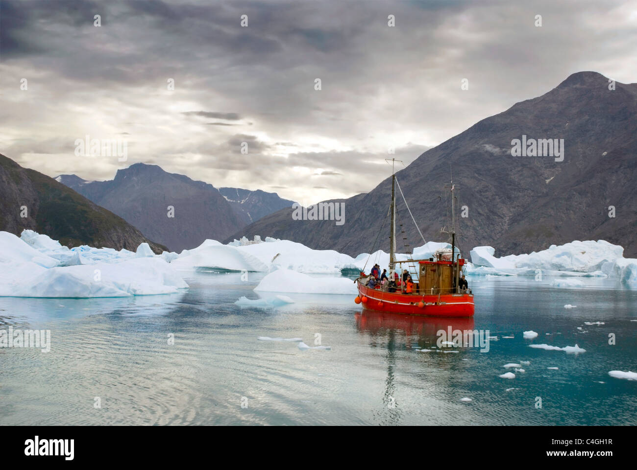 Iceberg and Icy waters with a small red boat in the foreground, taken ...