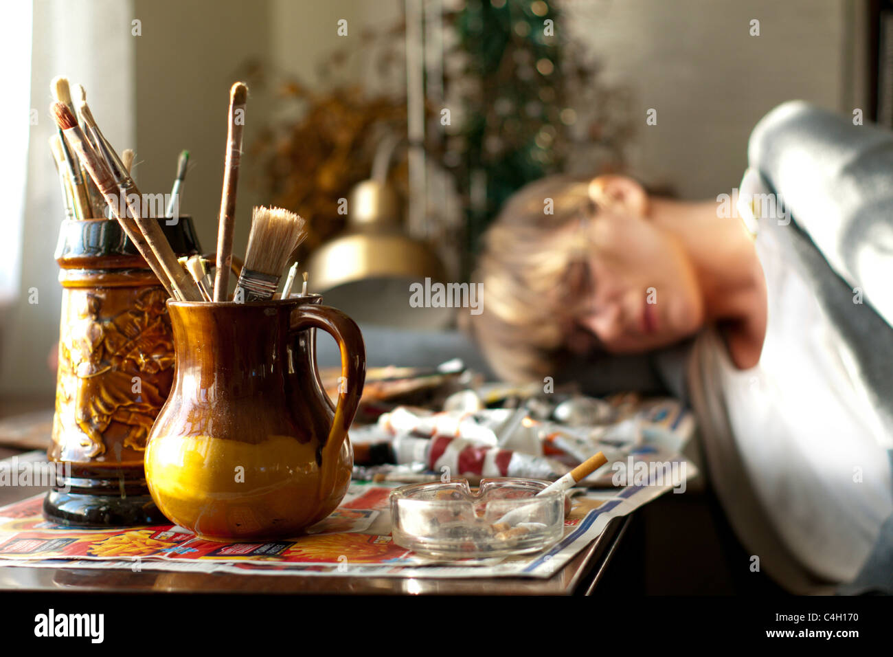 An artist sleeping on the table full of painting accessories Stock ...