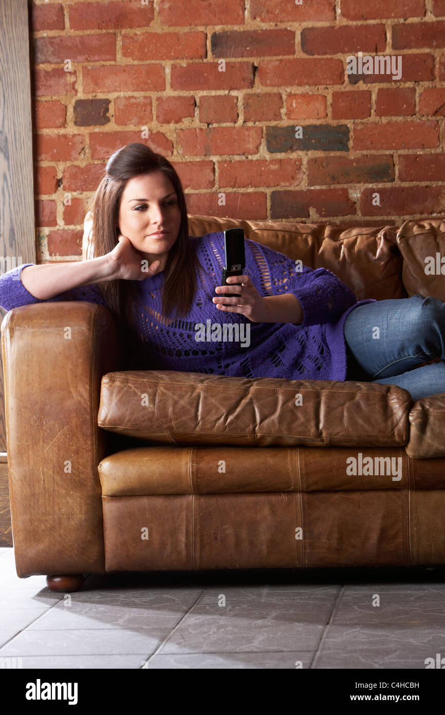 Young woman with phone on sofa Stock Photo - Alamy