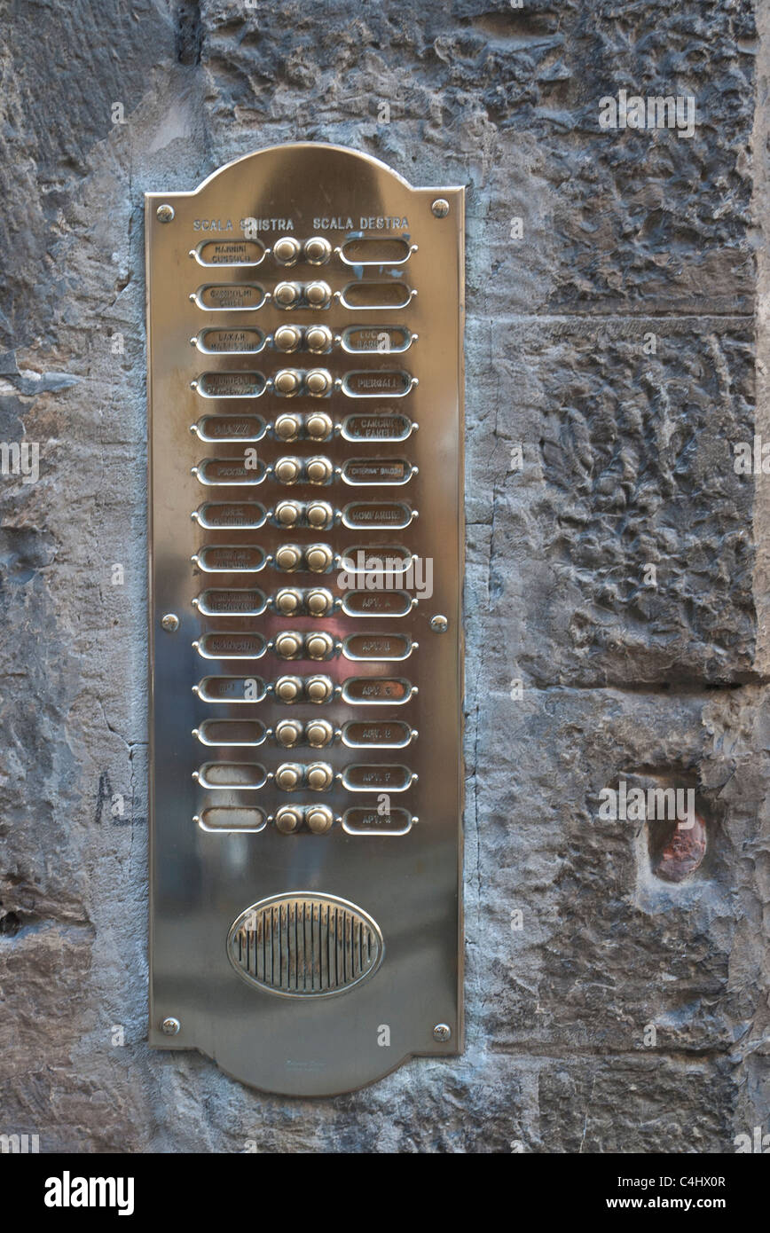 A polished brass plate with doorbells for building residents is ...