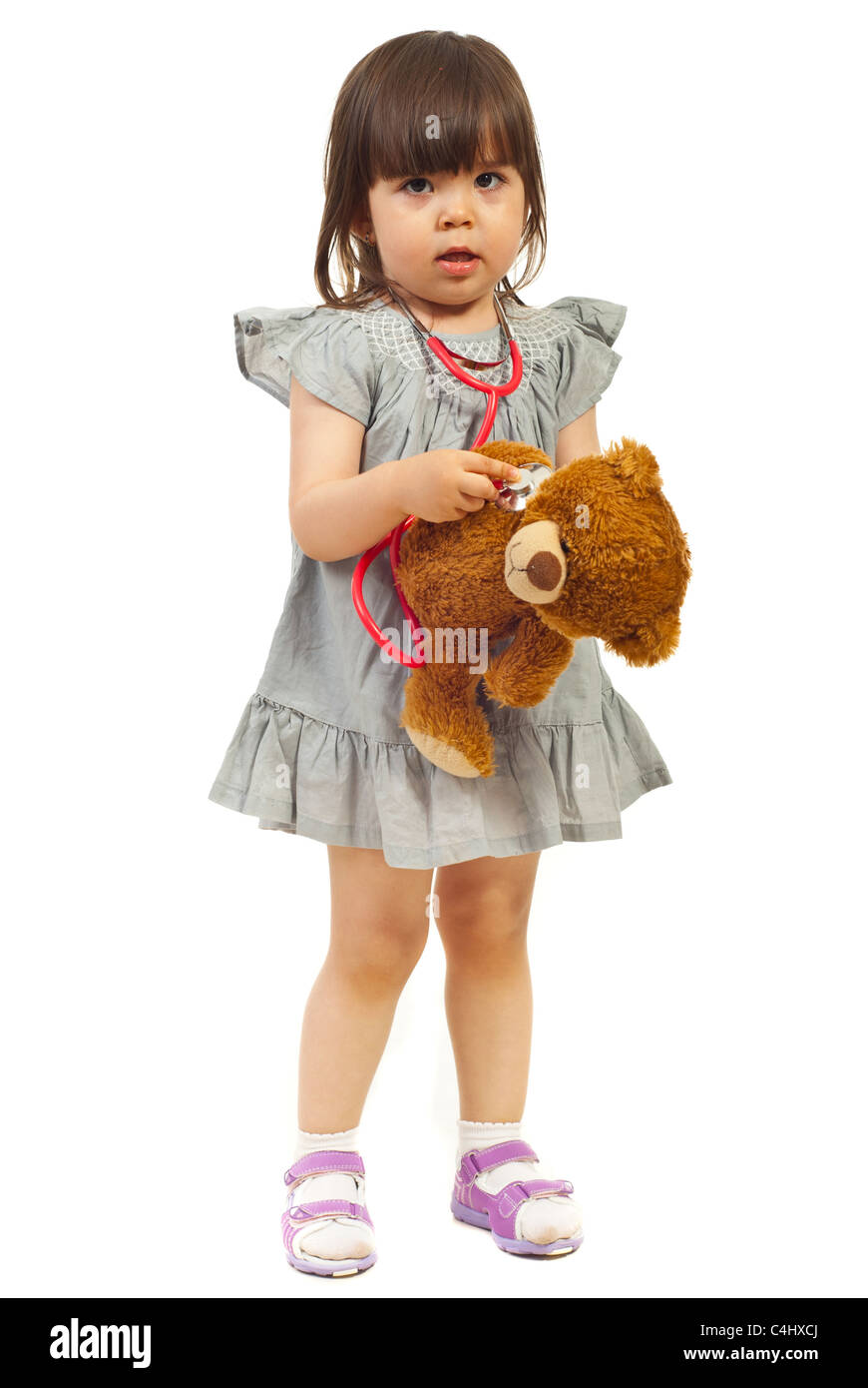 Little future doctor girl examine teddy bear with stethoscope isolated ...