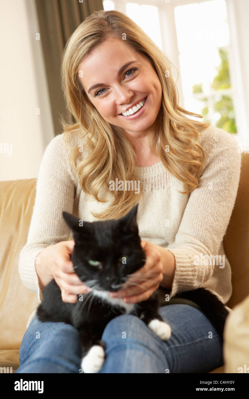 Happy young woman with cat sitting on sofa Stock Photo - Alamy